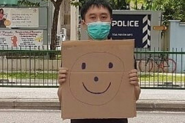 Singapore activist faces fine over one-man smiley face sign protest